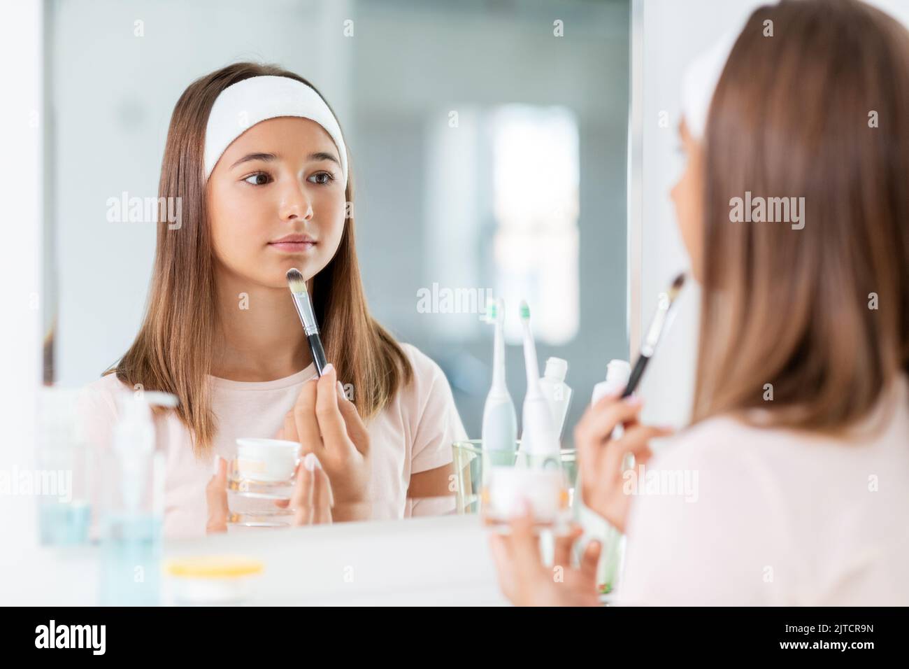teenage girl applying face mask at bathroom Stock Photo - Alamy