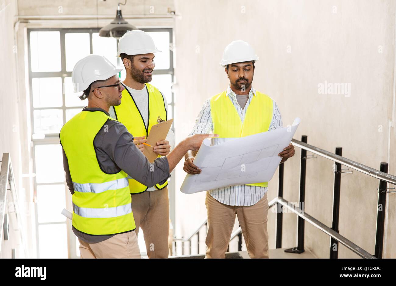 architects in helmets with blueprint at office Stock Photo - Alamy