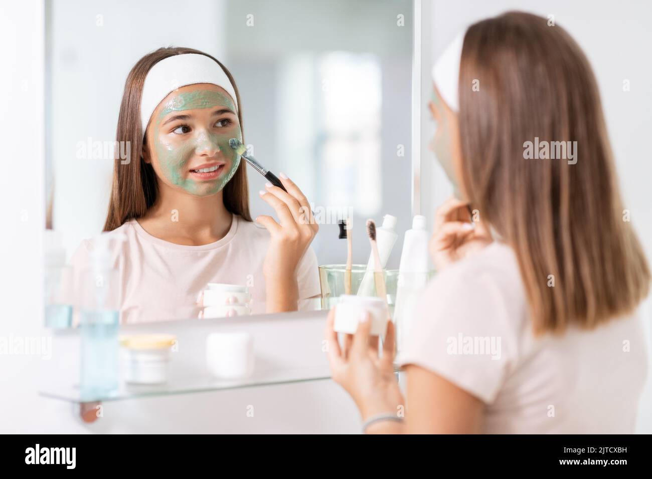 teenage girl applying mask to face at bathroom Stock Photo - Alamy