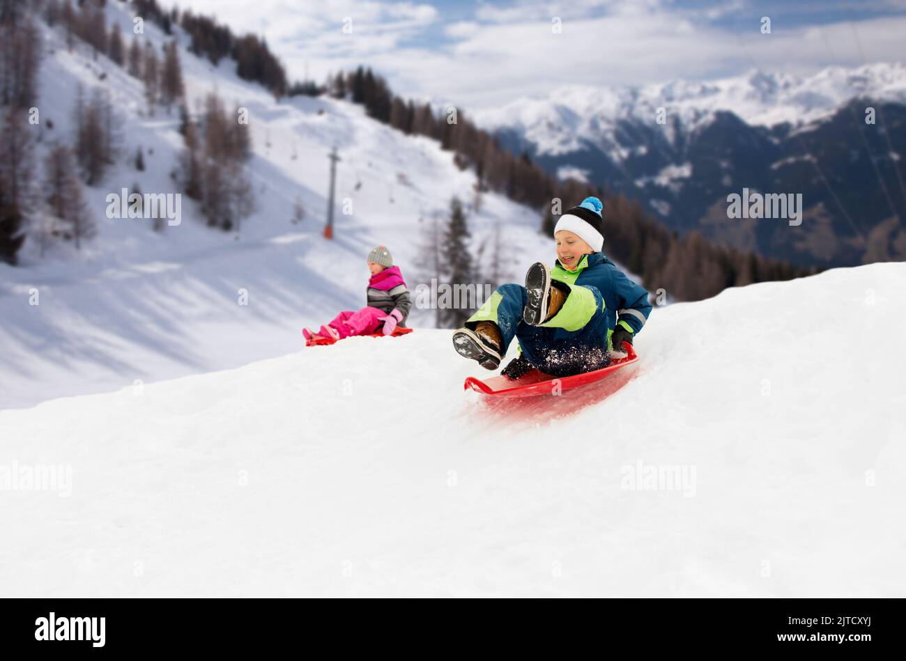 happy kids sliding on sleds down hill in winter Stock Photo - Alamy