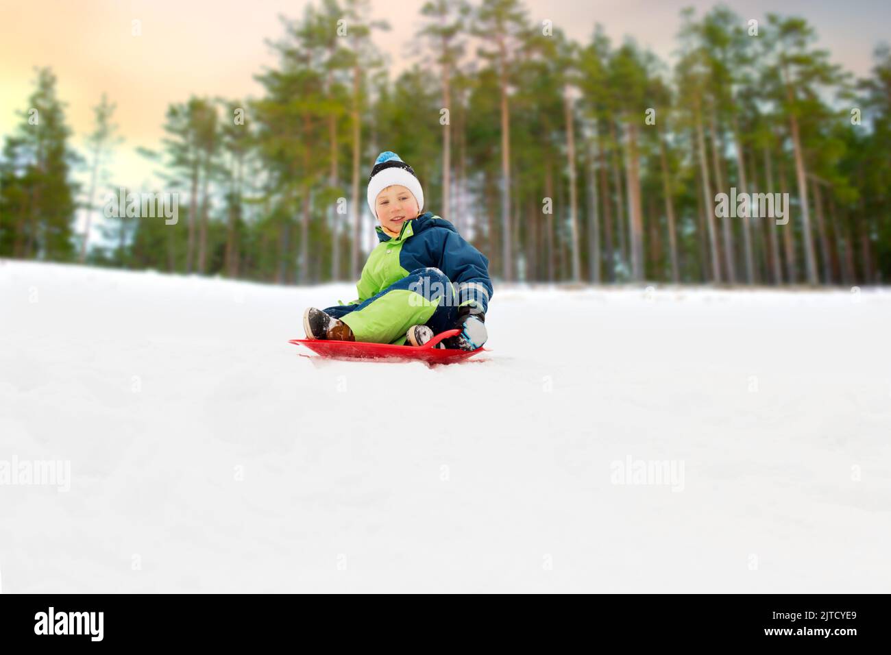 happy boy sliding on sled down snow hill in winter Stock Photo - Alamy
