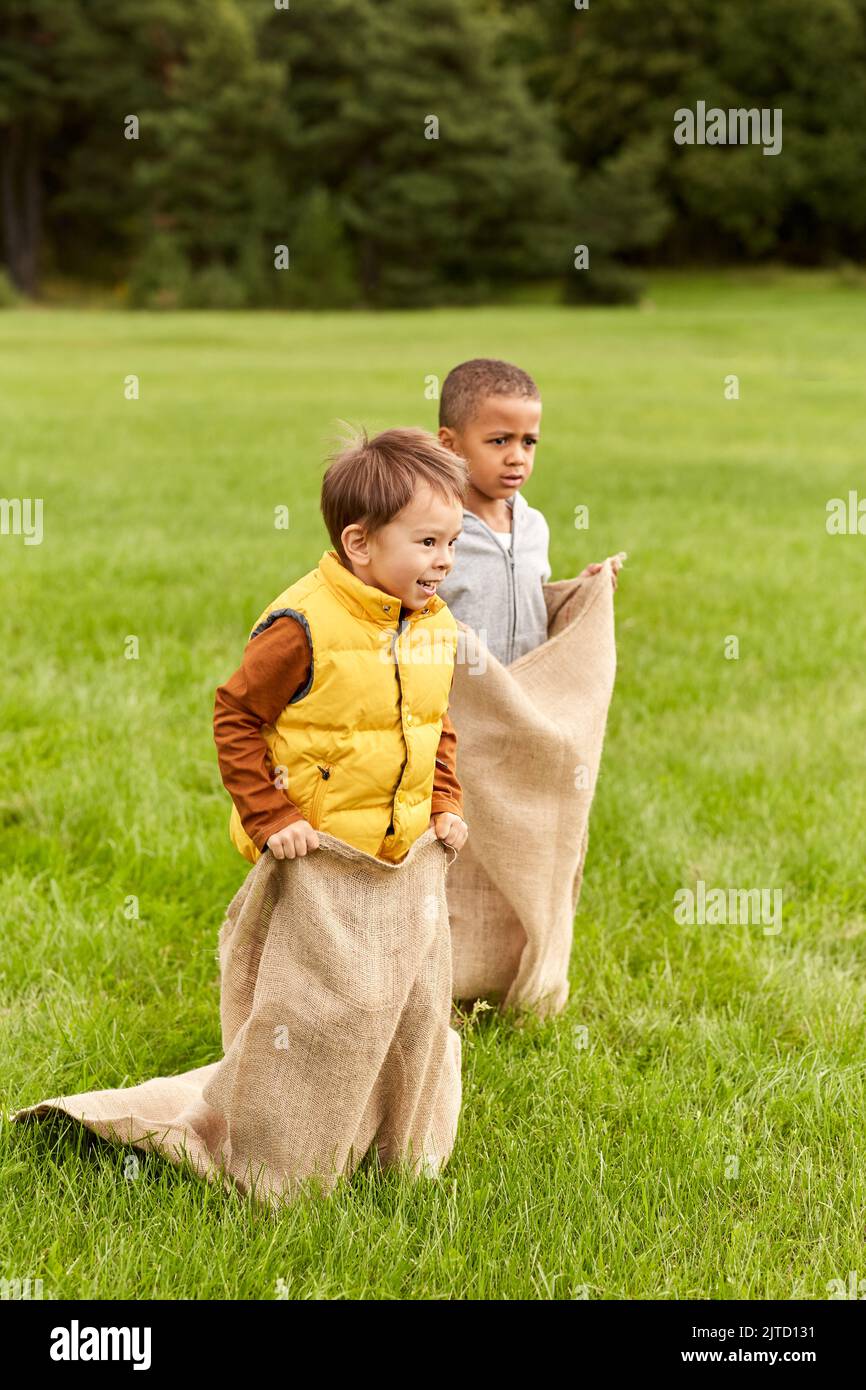happy boys playing bag jumping game at park Stock Photo - Alamy