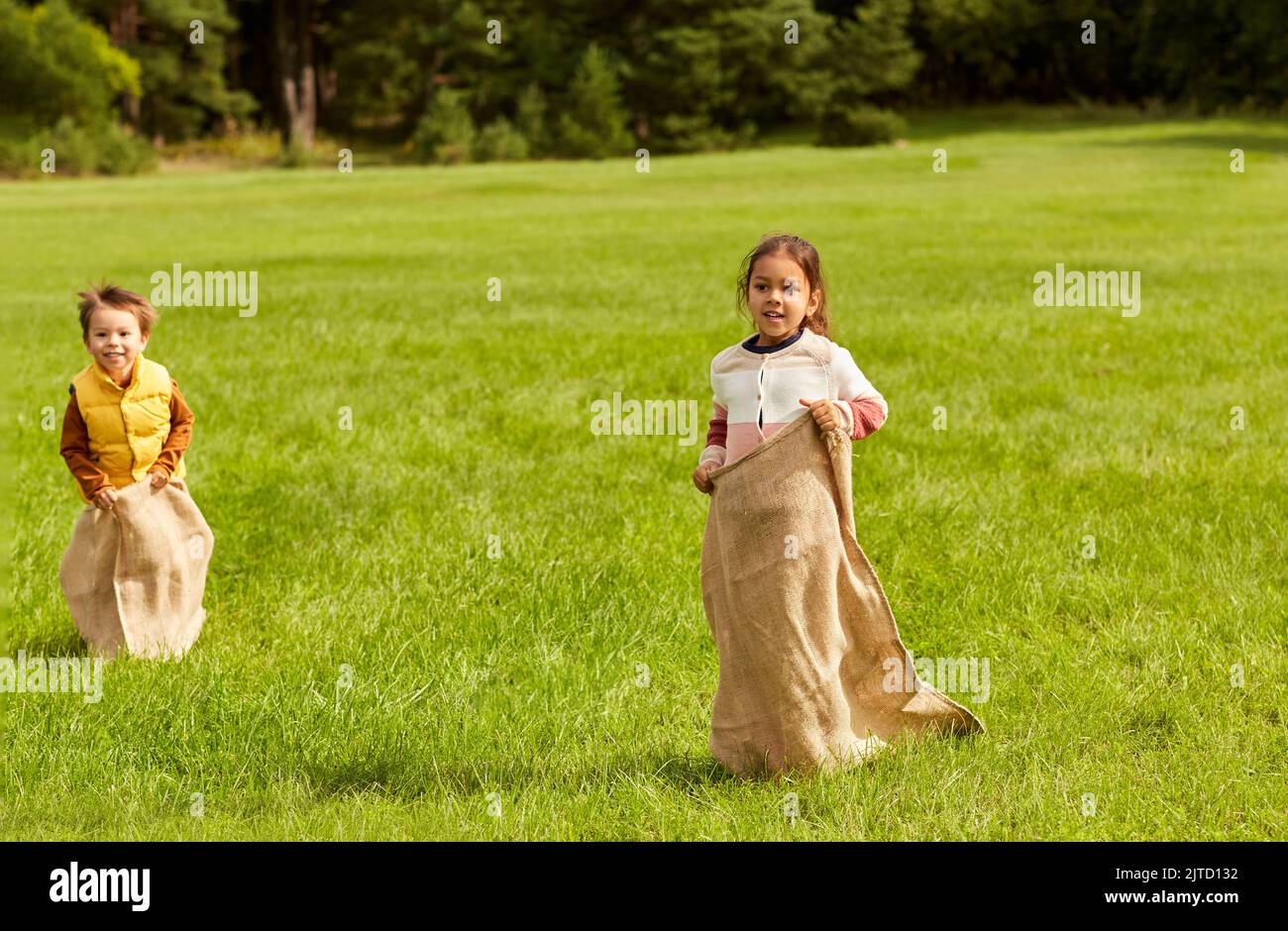 happy children playing bag jumping game at park Stock Photo - Alamy