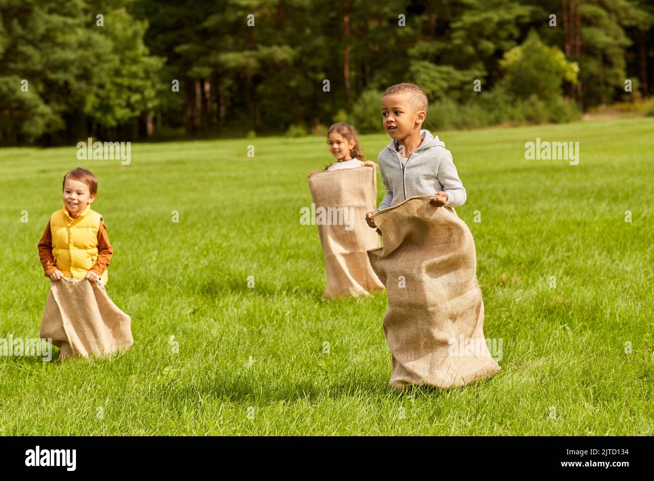happy children playing bag jumping game at park Stock Photo - Alamy