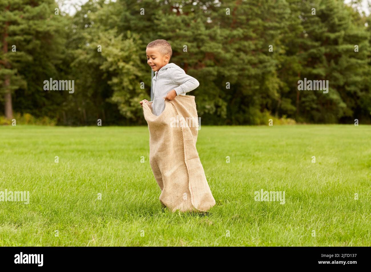 happy boy playing bag jumping game at park Stock Photo - Alamy