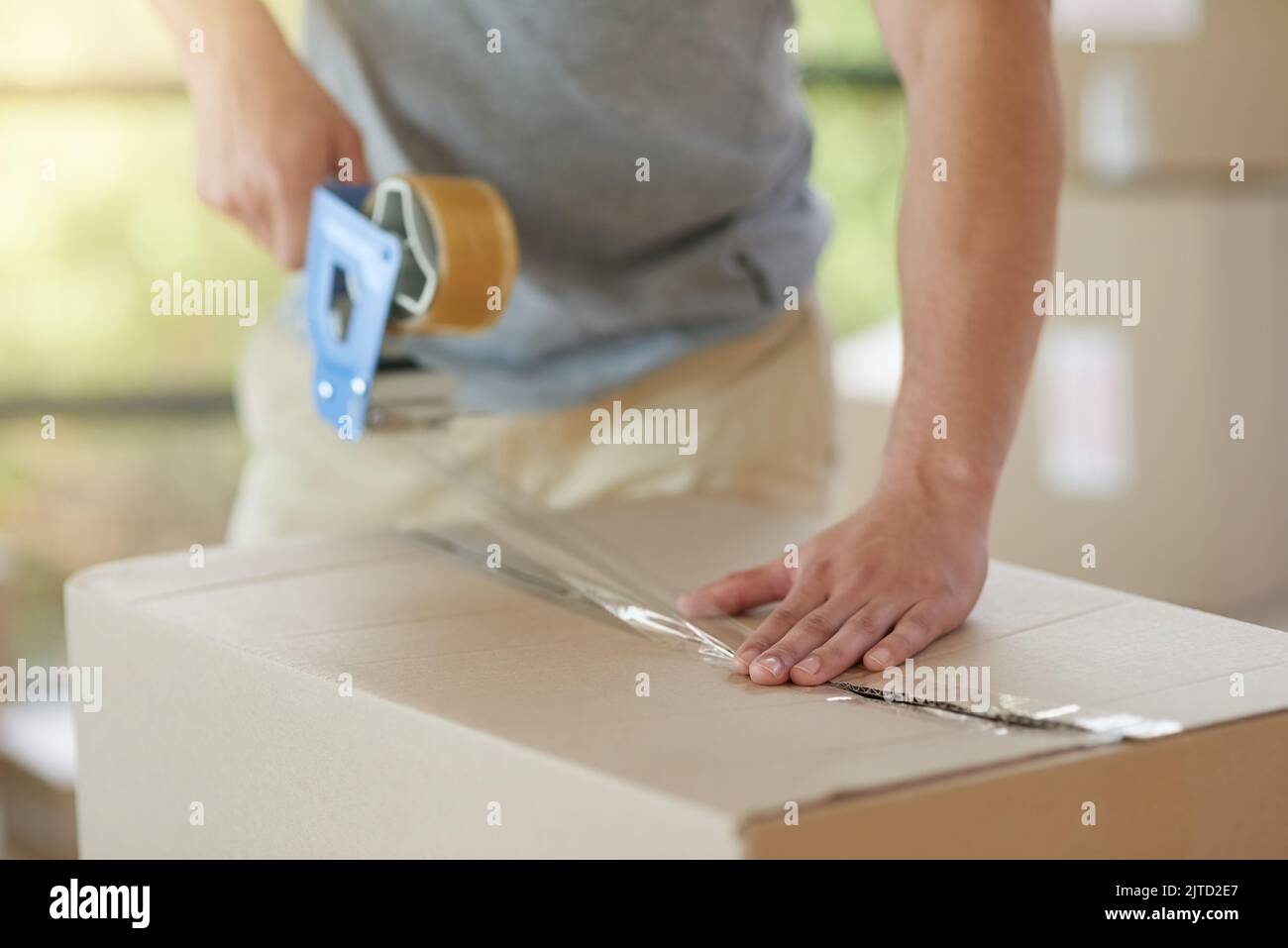 Packed safe and snug. an unidentifiable young man closing a cardboard ...