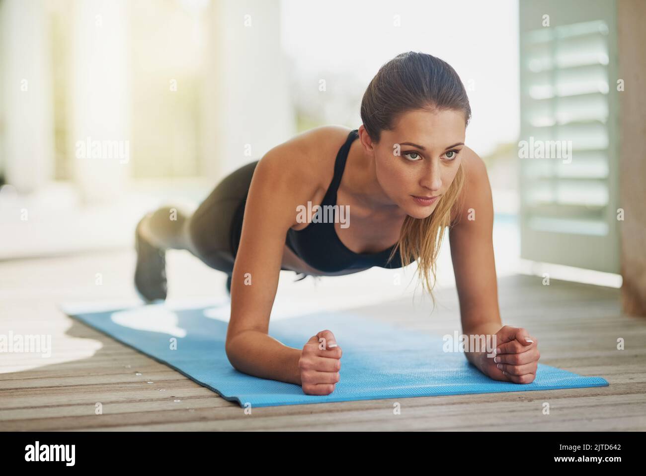 Building upper body strength. an attractive young woman planking on her ...