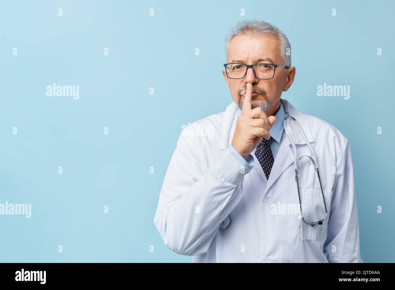 Portrait of a doctor showing silence gesture. Medical secret concept ...
