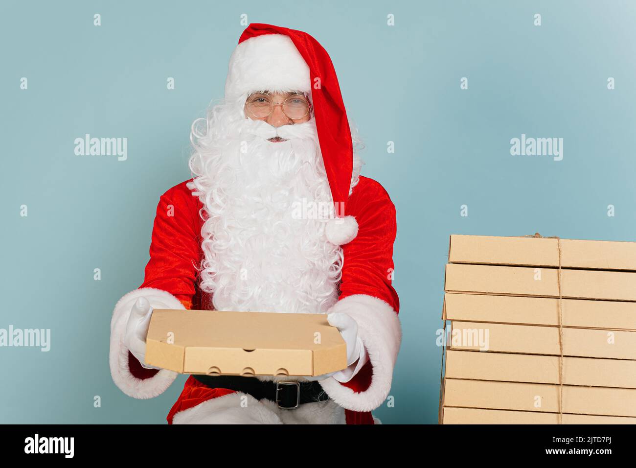 Santa claus holds out a closed pizza box holding it with his hands on a ...