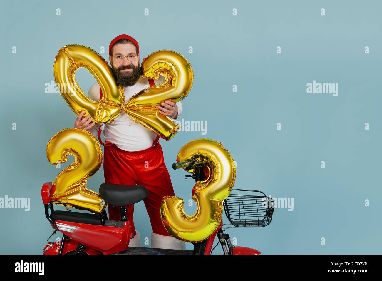 Young adult man in a santa costume and suspenders holds inflatable ...