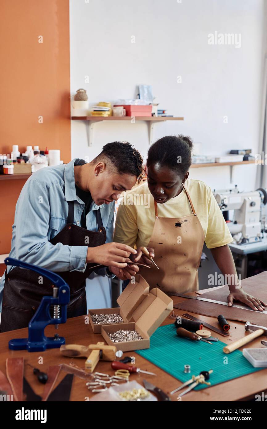 Vertical portrait of two female artisans in leatherworking shop ...