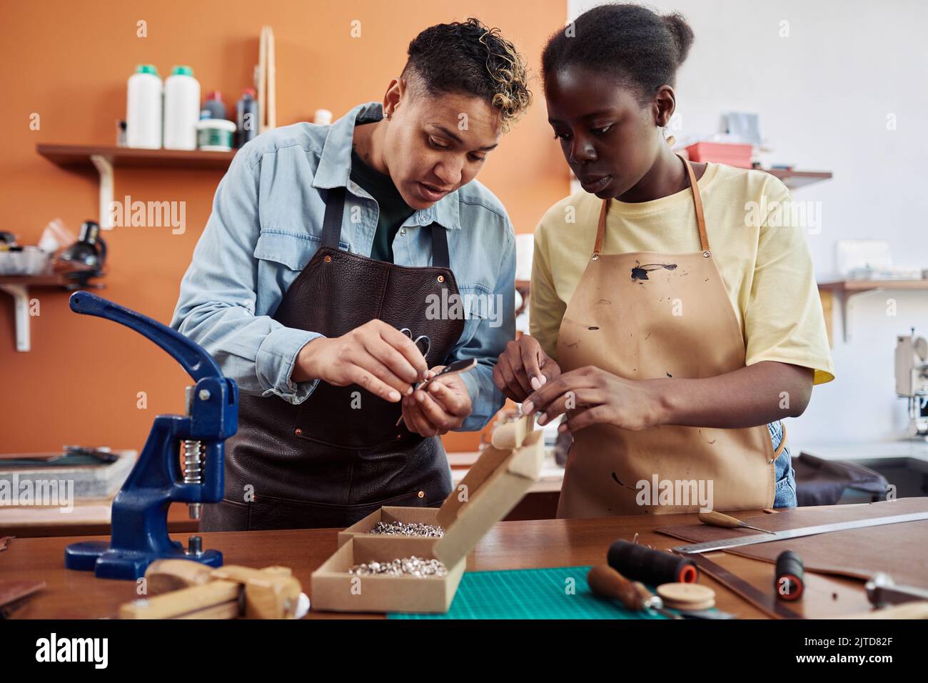 Waist up portrait of two female artisans in leatherworking shop ...