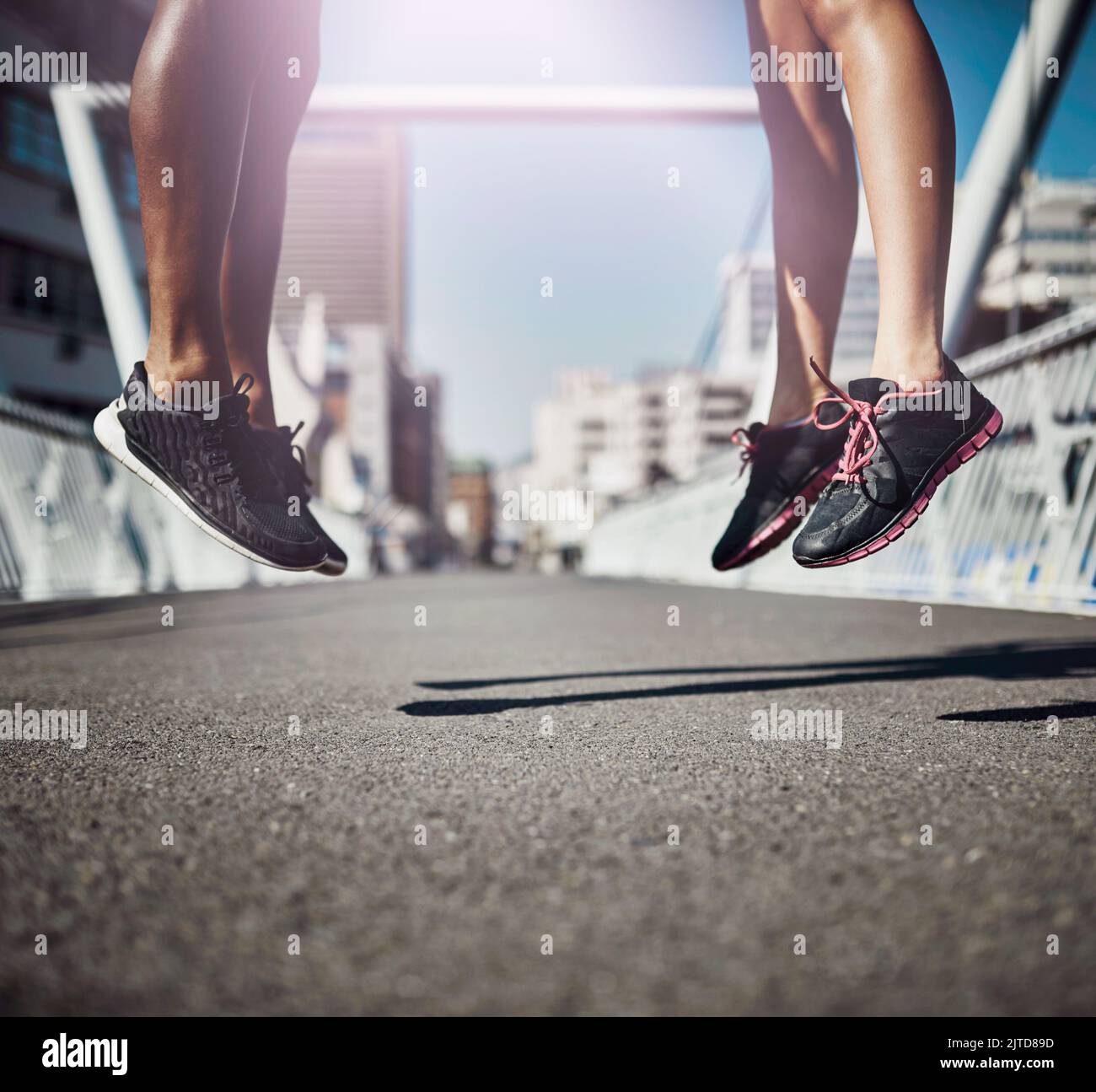 Raise your game. Legs-only shot of two sporty people jumping on a ...