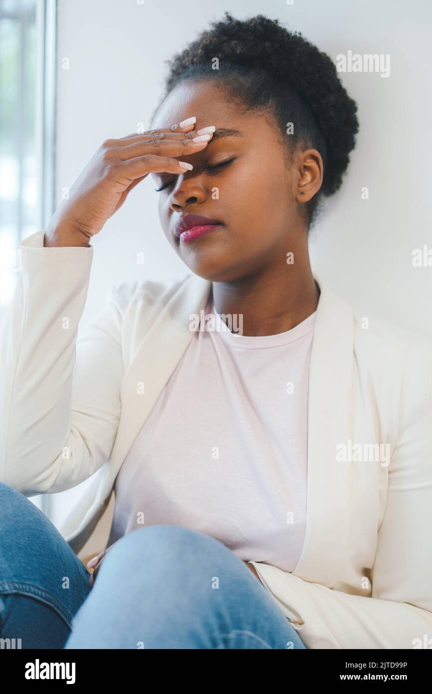 Closeup portrait unhappy afro young businesswoman sitting alone at the ...