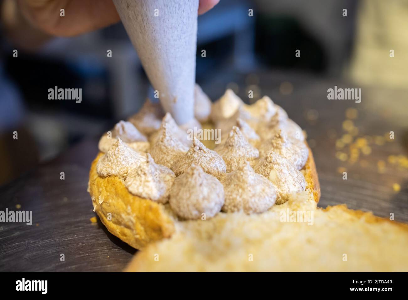 A baker fills brioche cream in a craft bakery. A close-up photo. Front ...