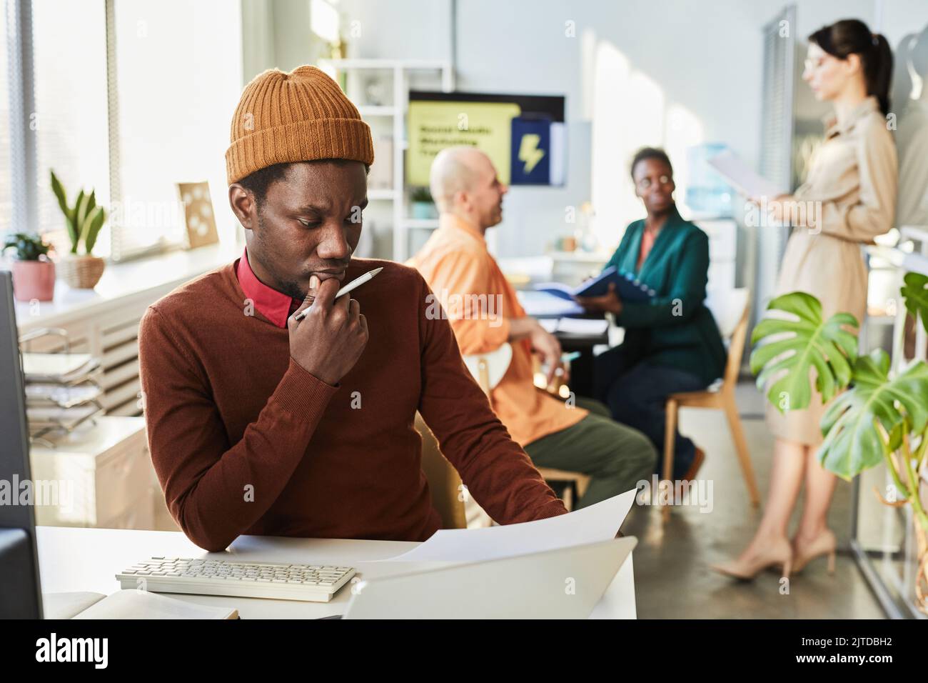 Portrait of creative black man planning project and reading document at ...