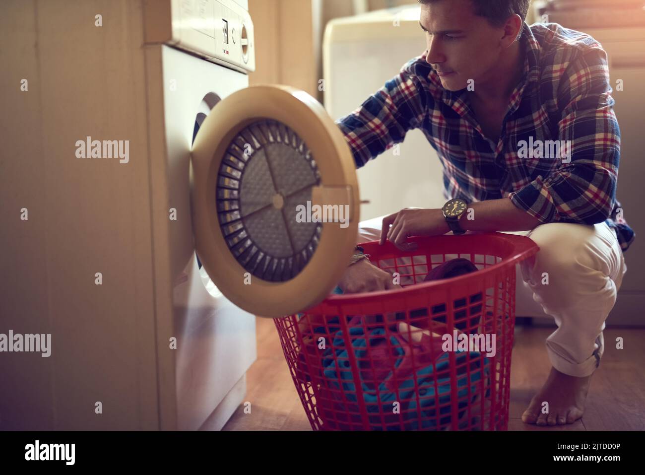 Real men do the laundry. a young man doing laundry at home Stock Photo ...