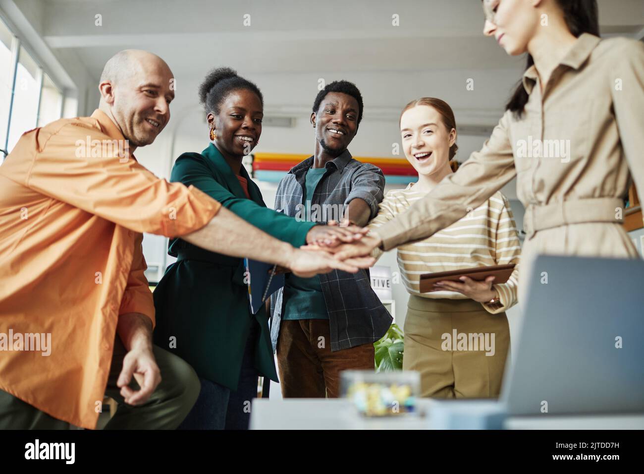 Low angle view at diverse business team huddling in office and stacking ...