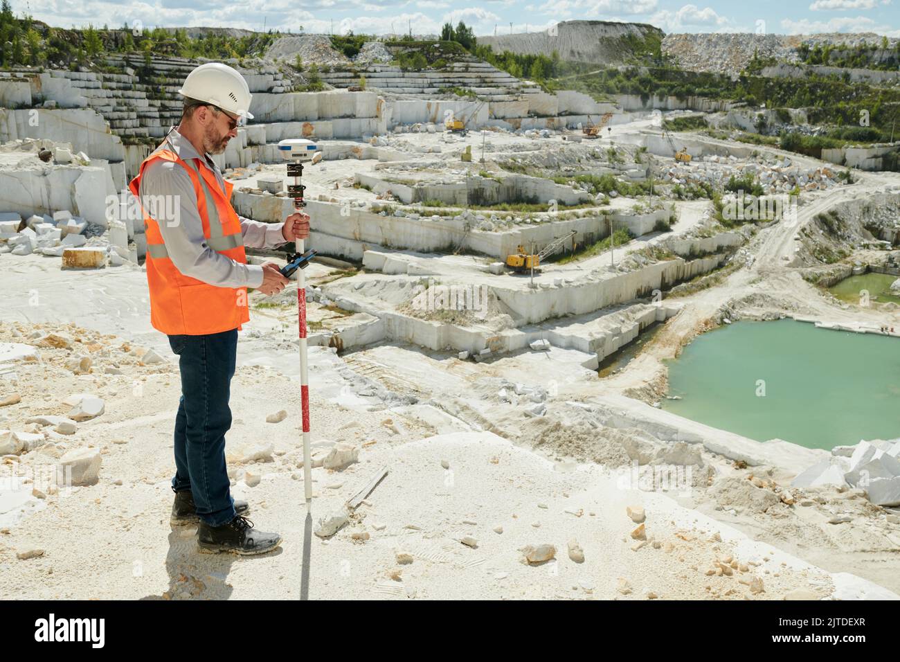 Male worker of marble quarry standing on its territory and adjusting ...