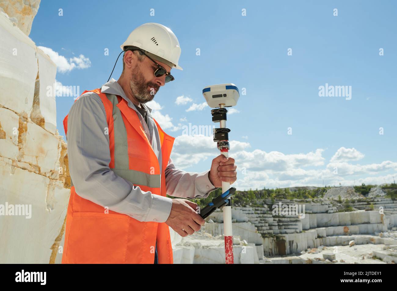 Confident engineer or surveyor with geodesic equipment standing on ...
