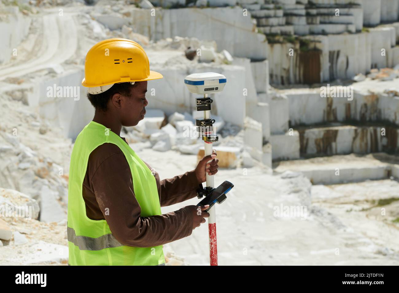 Young African American female surveyor in uniform and protective helmet ...