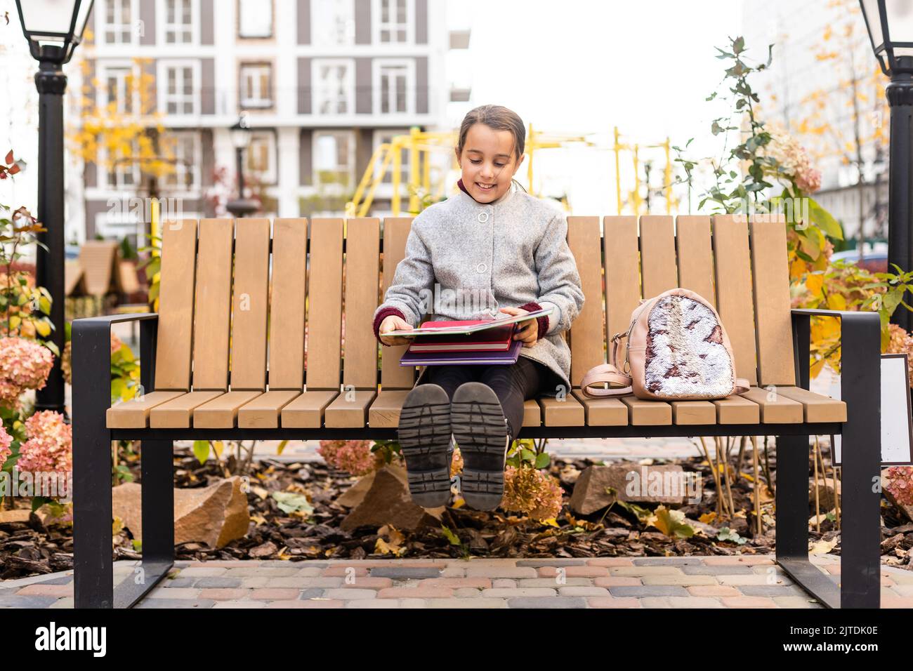 Schoolgirl reading book while sitting on bench in park Stock Photo - Alamy