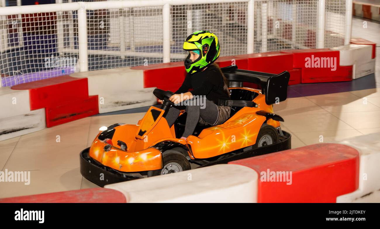 a the smiling little girl in a helmet in the go-kart on the karting ...
