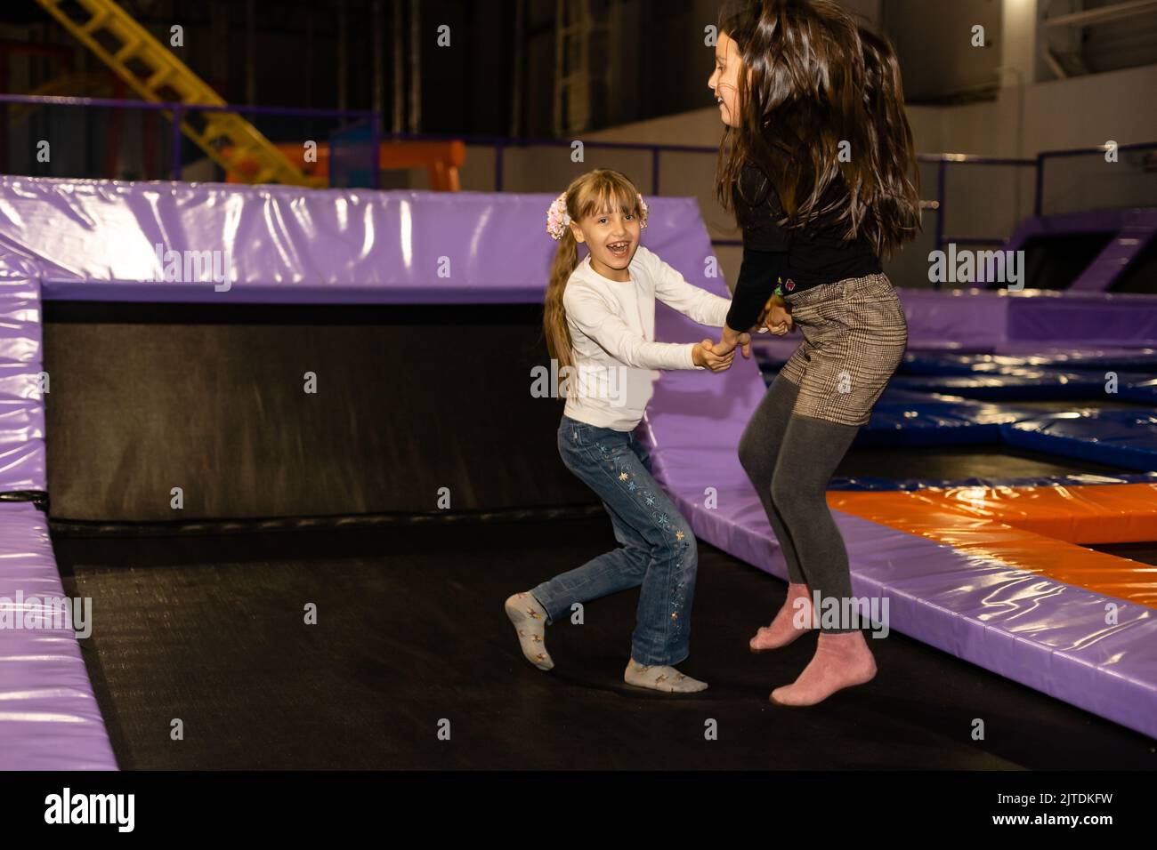 Little pretty girls having fun. Jumping on trampoline in children zone ...