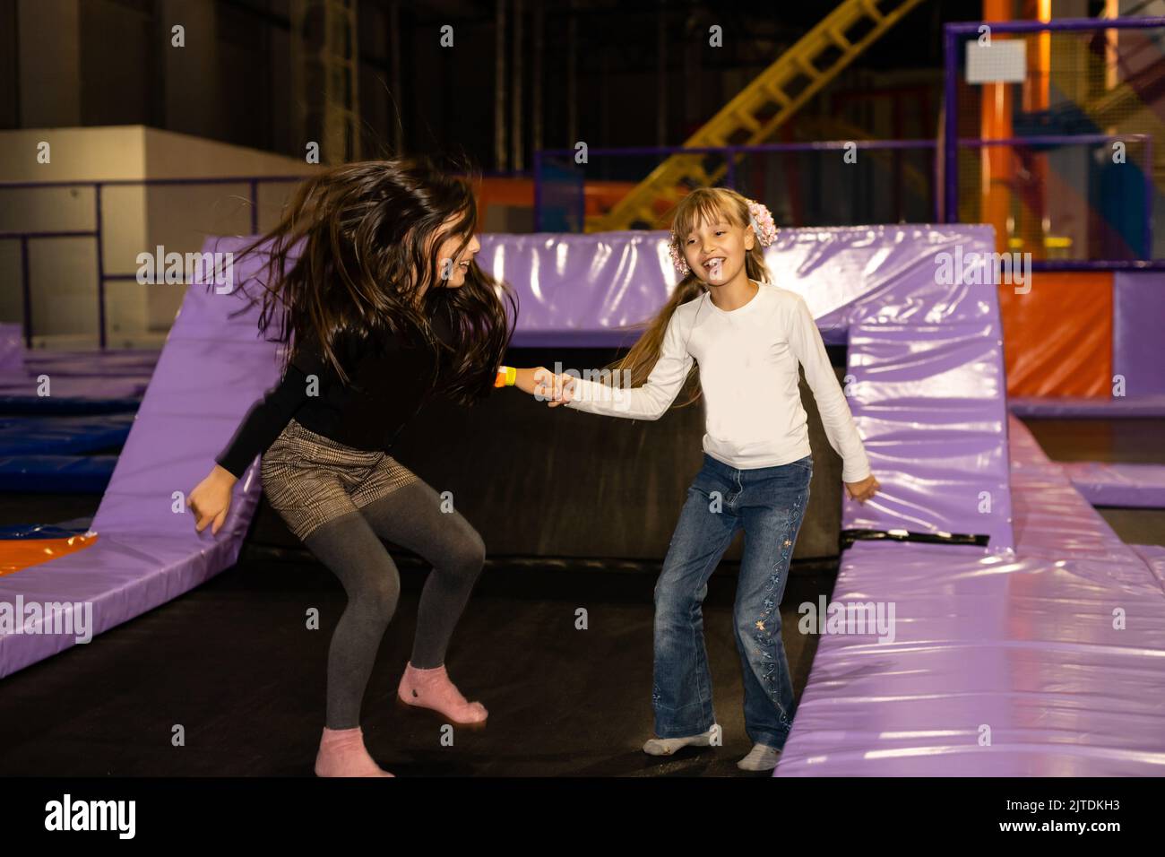 Little pretty girls having fun. Jumping on trampoline in children zone ...