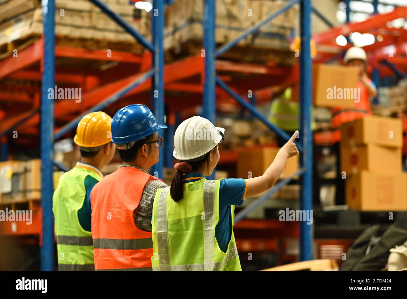 Rear view of manager and workers in hardhats and reflective jackets ...