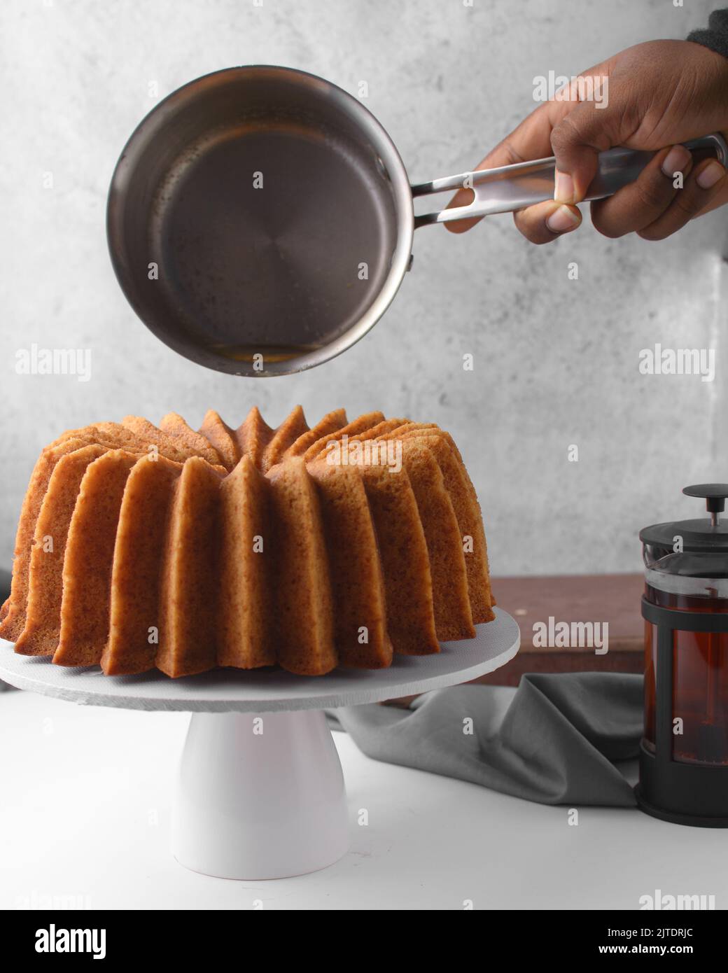 Female hand Pouring a rum sauce on rum bundt cake Stock Photo - Alamy