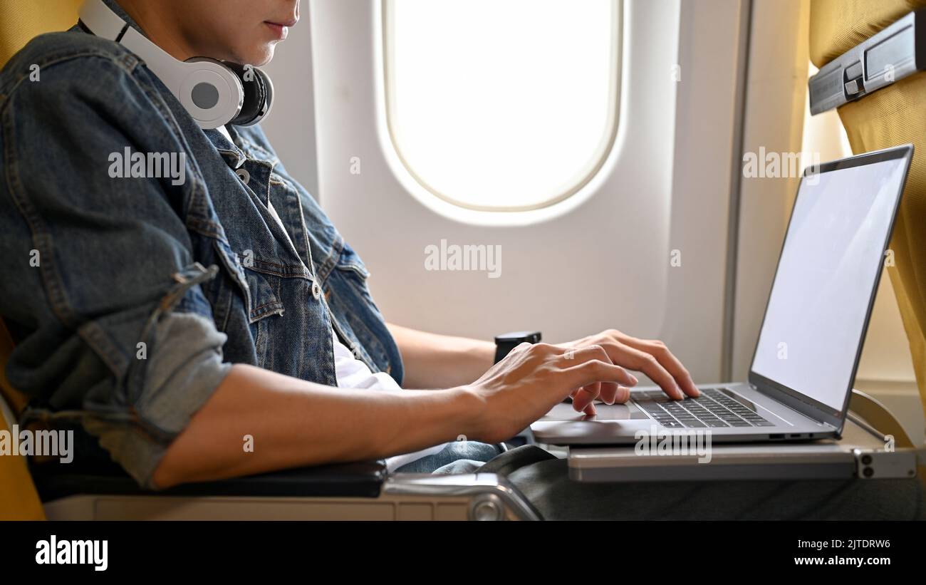 A hipster young Asian male passenger using his laptop computer, working ...