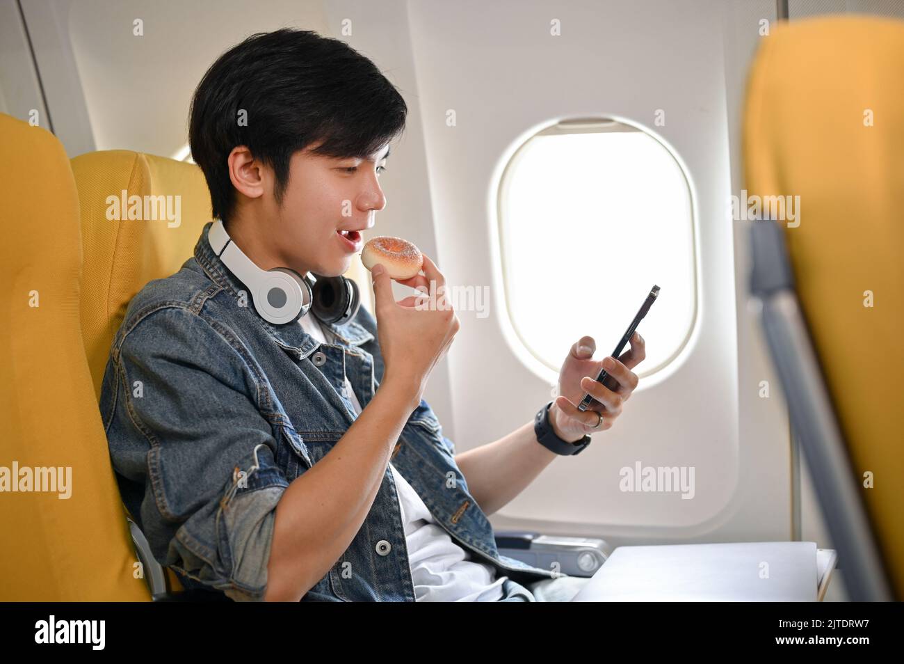 Happy and relaxed young Asian male passenger in an economy class ...