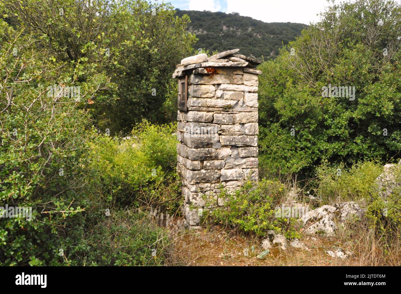 Traditional Greek stone memorial amongst a forest in mountainous Greece ...