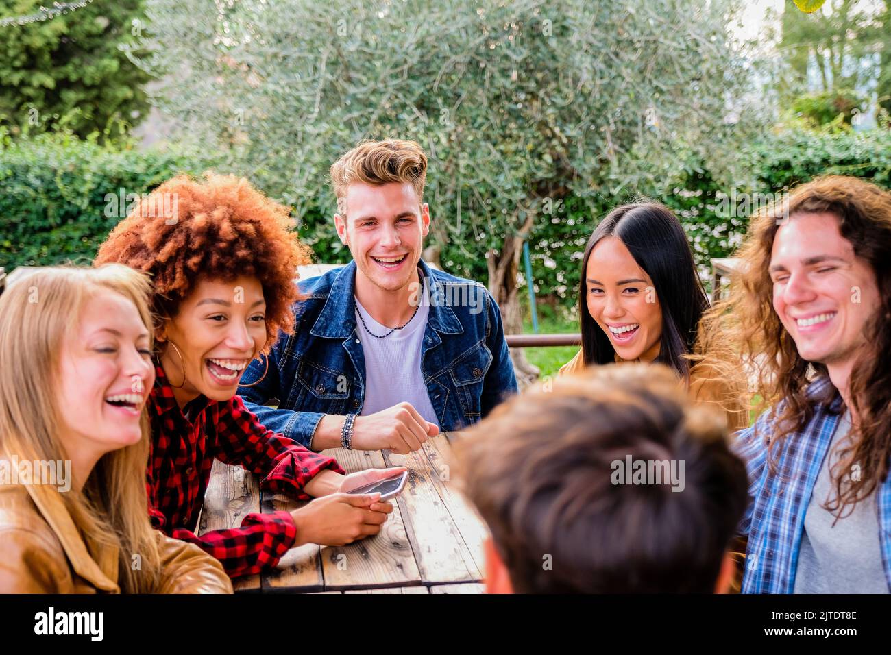 Group of young people sitting in a cafe and smiling and looking theyr smartphone - Happy ...