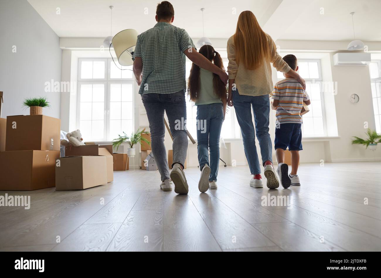 Back view of a young man, woman and children entering their new house ...