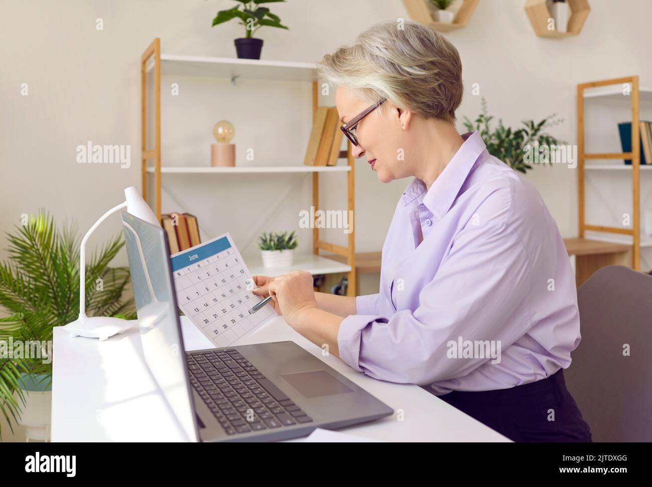 Senior successful business woman planning her work week and checking ...