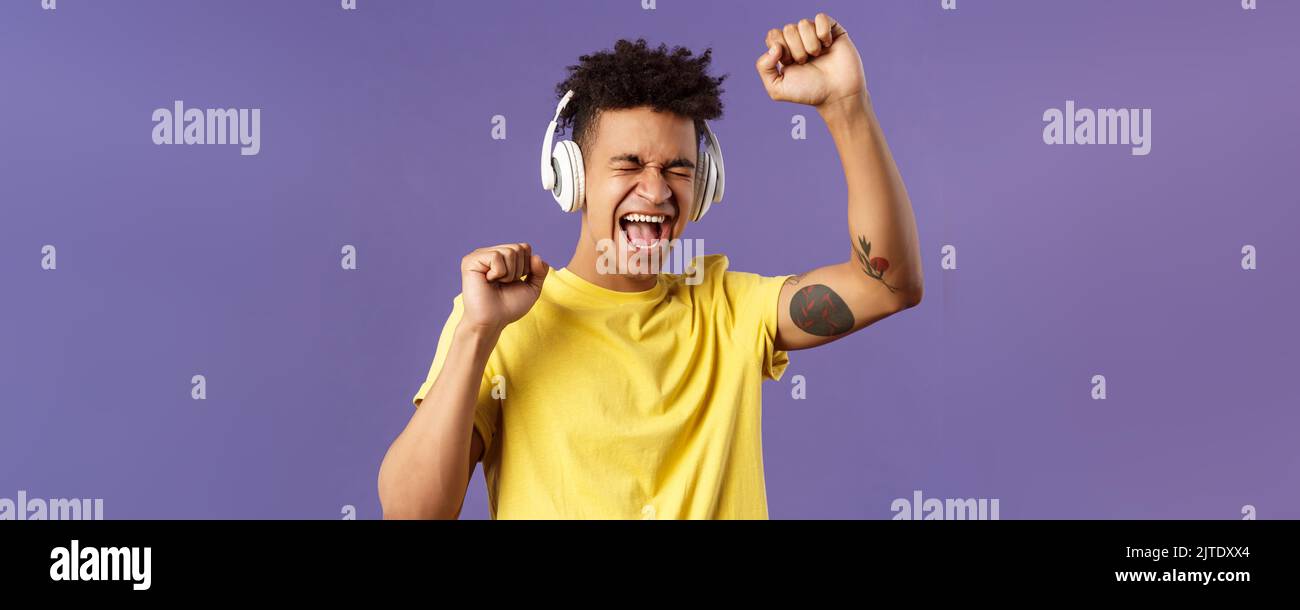 Close-up portrait of cheerful, happy young dancing guy lift hand up ...