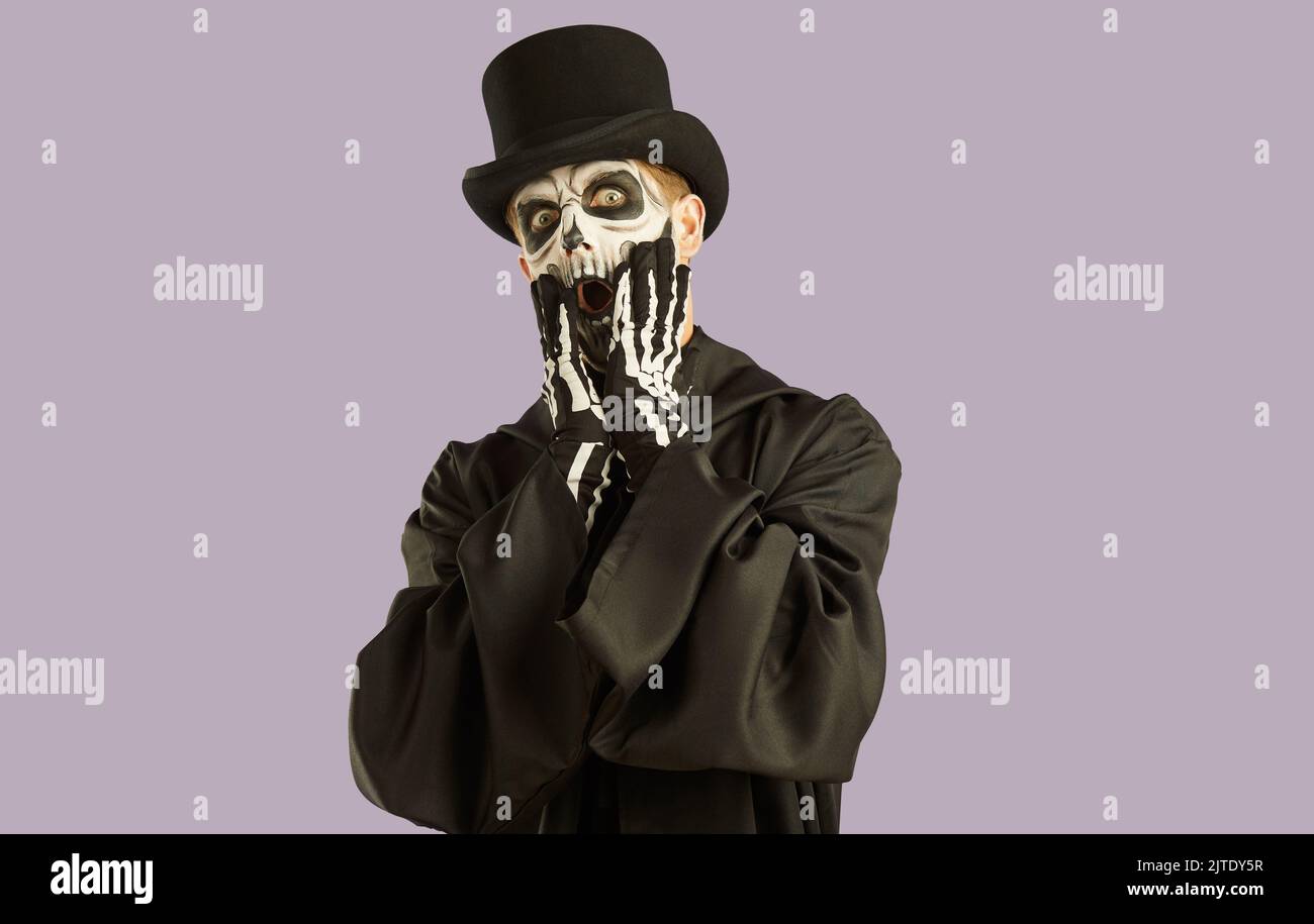 Portrait of shocked man in Halloween make-up and costume grabbing his ...