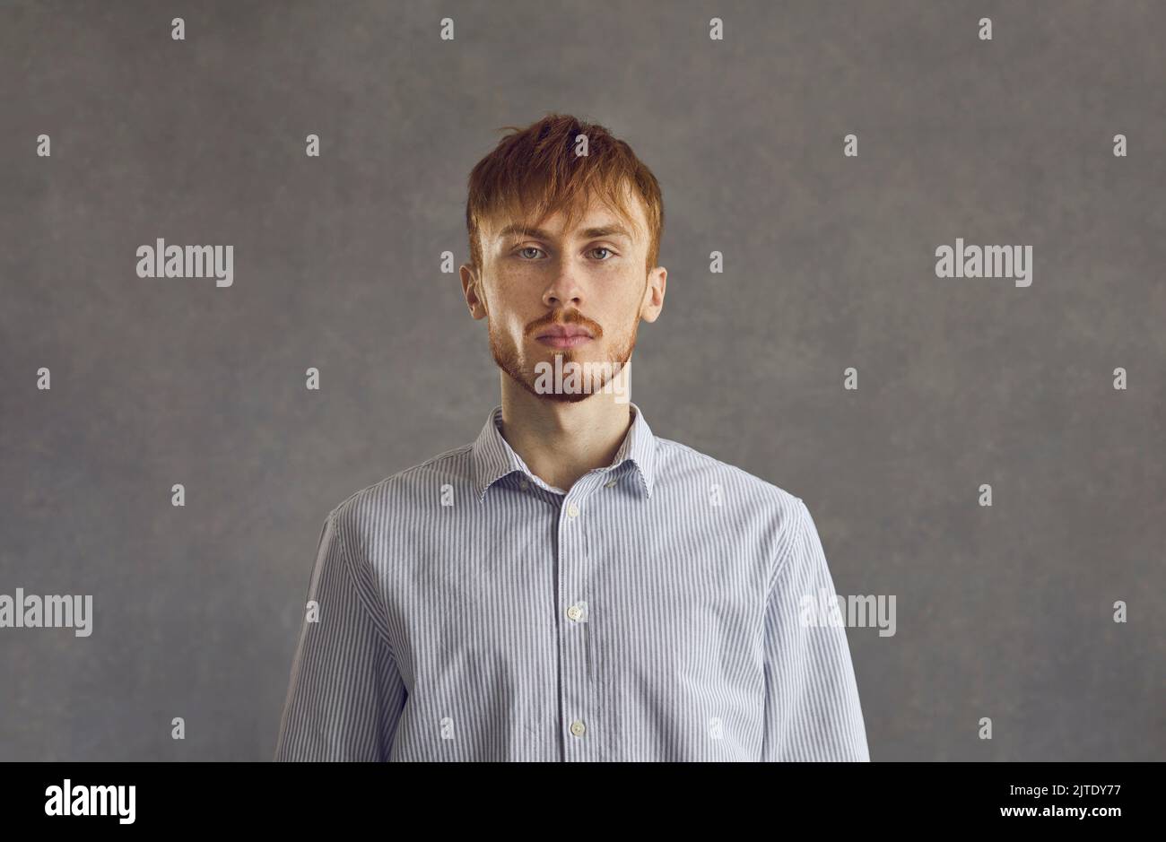 Serious red-haired man headshot studio face portrait over grey ...