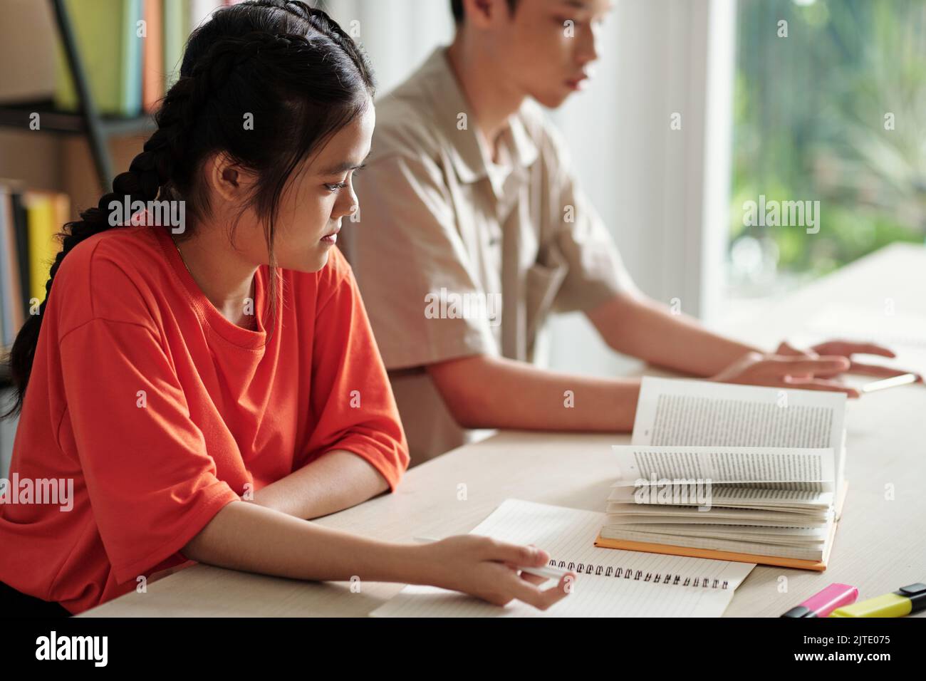School children sitting at school desk and reading book for English ...