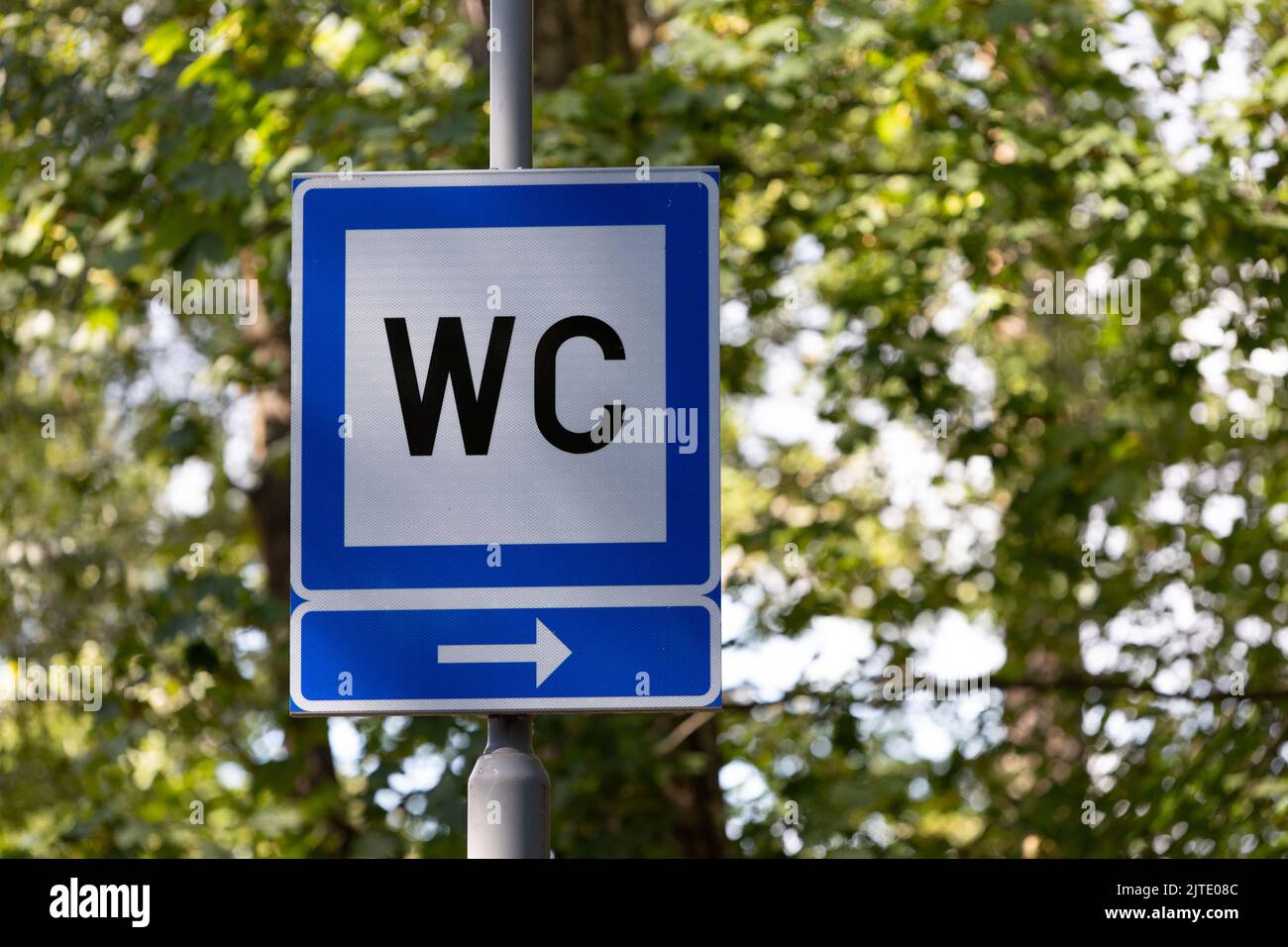 A closeup shot of a sign showing the direction of a toilet for women in ...