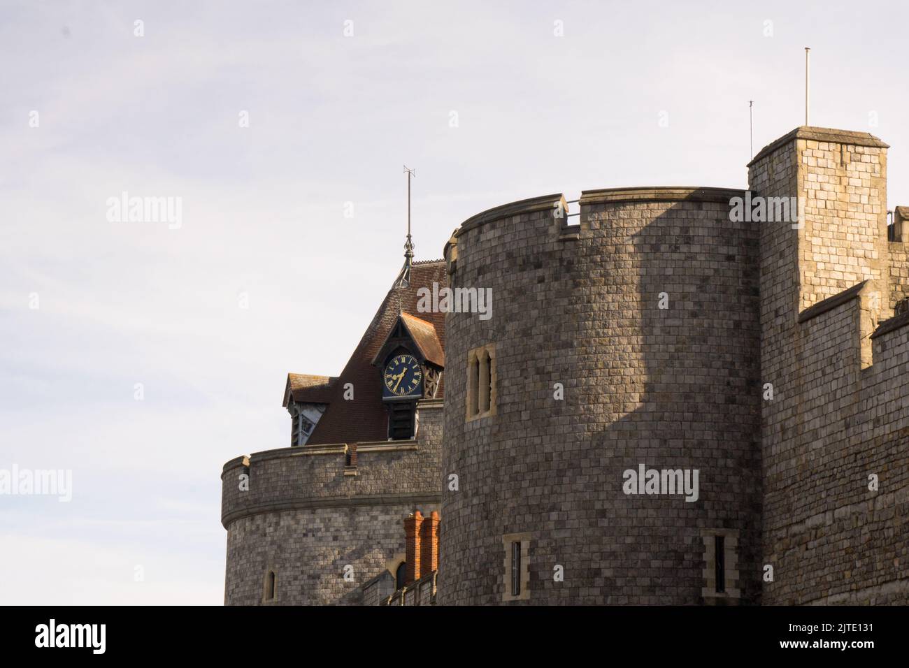 Windsor castle partial view with towers roofs and clock against blue ...