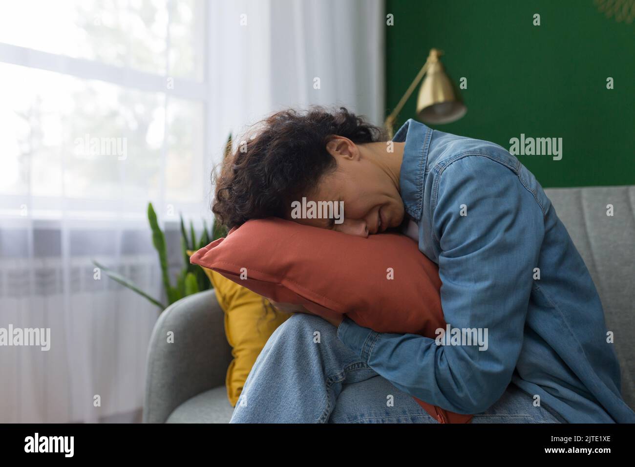 Woman at home crying sitting on sofa hugging pillow, Hispanic woman ...