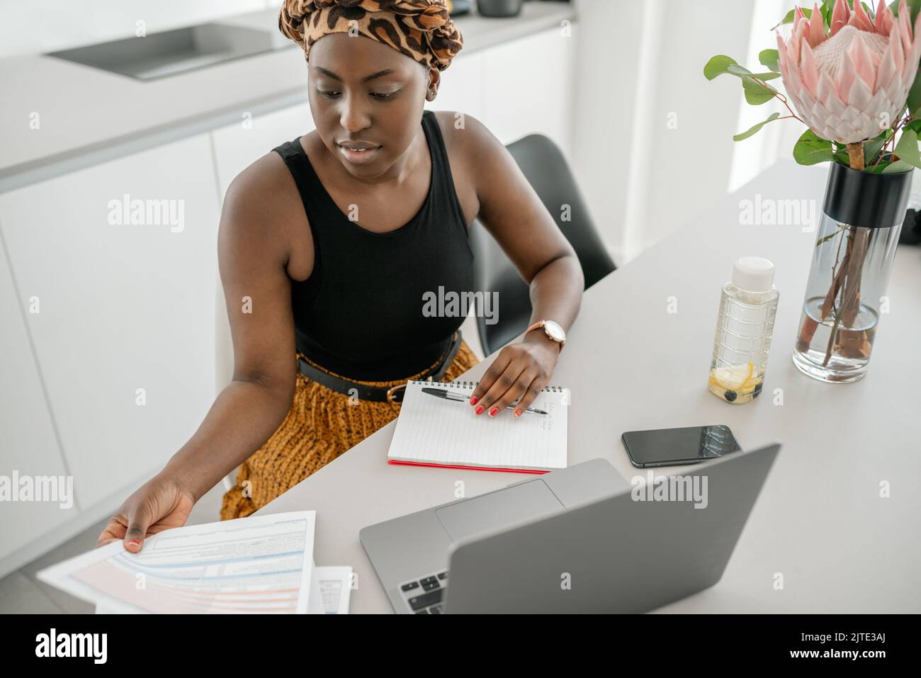 Black African woman working from home, going through paperwork and ...