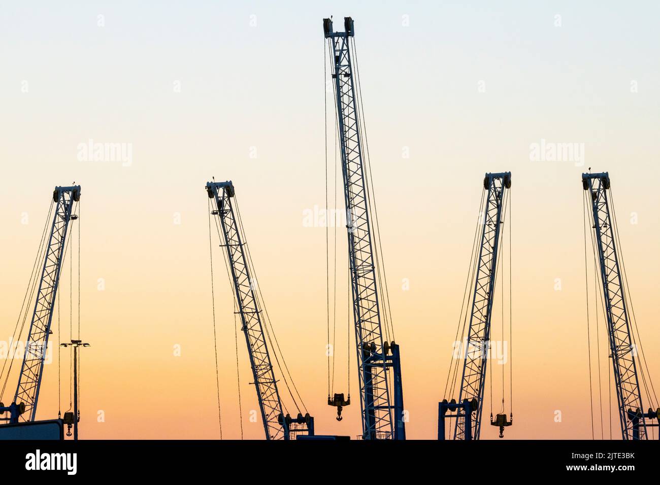 Dockyard cranes silhouetted against the sunset, in the port of ...