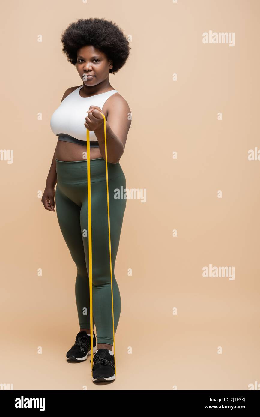 full length of african american plus size woman in sportwear exercising ...