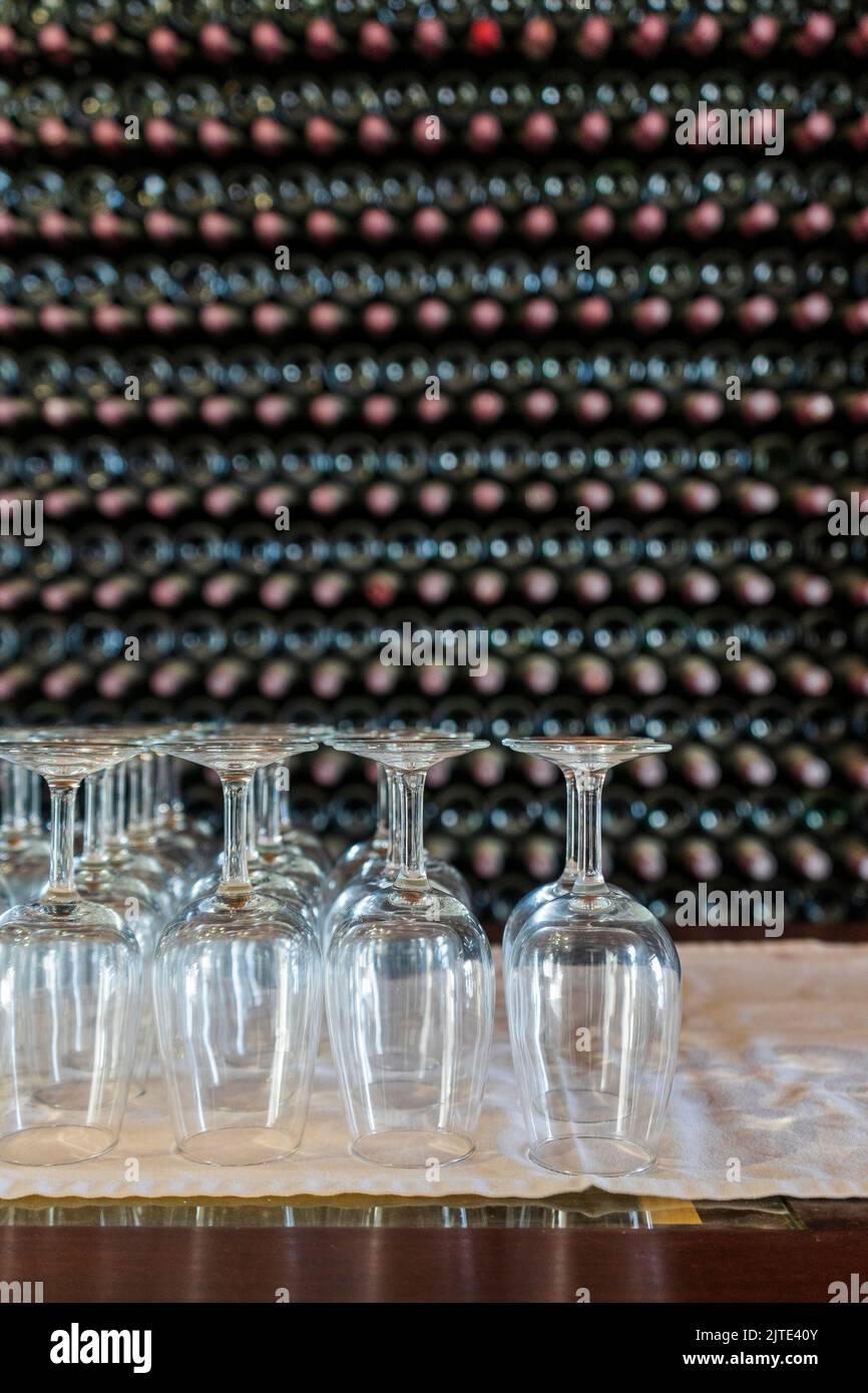 Empty wine glasses with many stacked bottles as a background ...