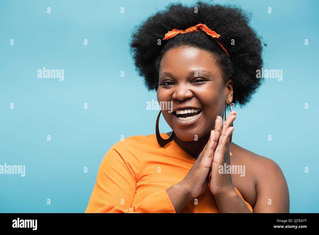 Happy African American Body Positive Woman In Orange Dress And Hoop