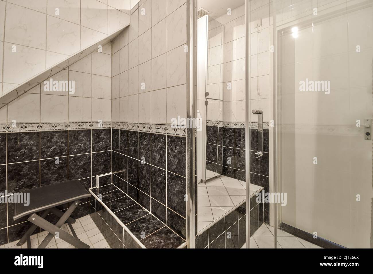 Shower faucets attached to tiled wall near glass partition and washing ...